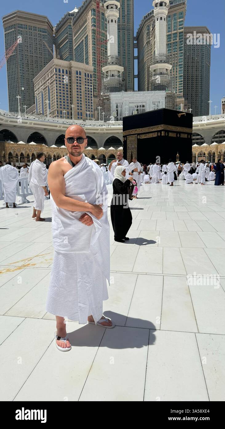 A bald man poses for a photo in front of the Kaaba at noon after ...