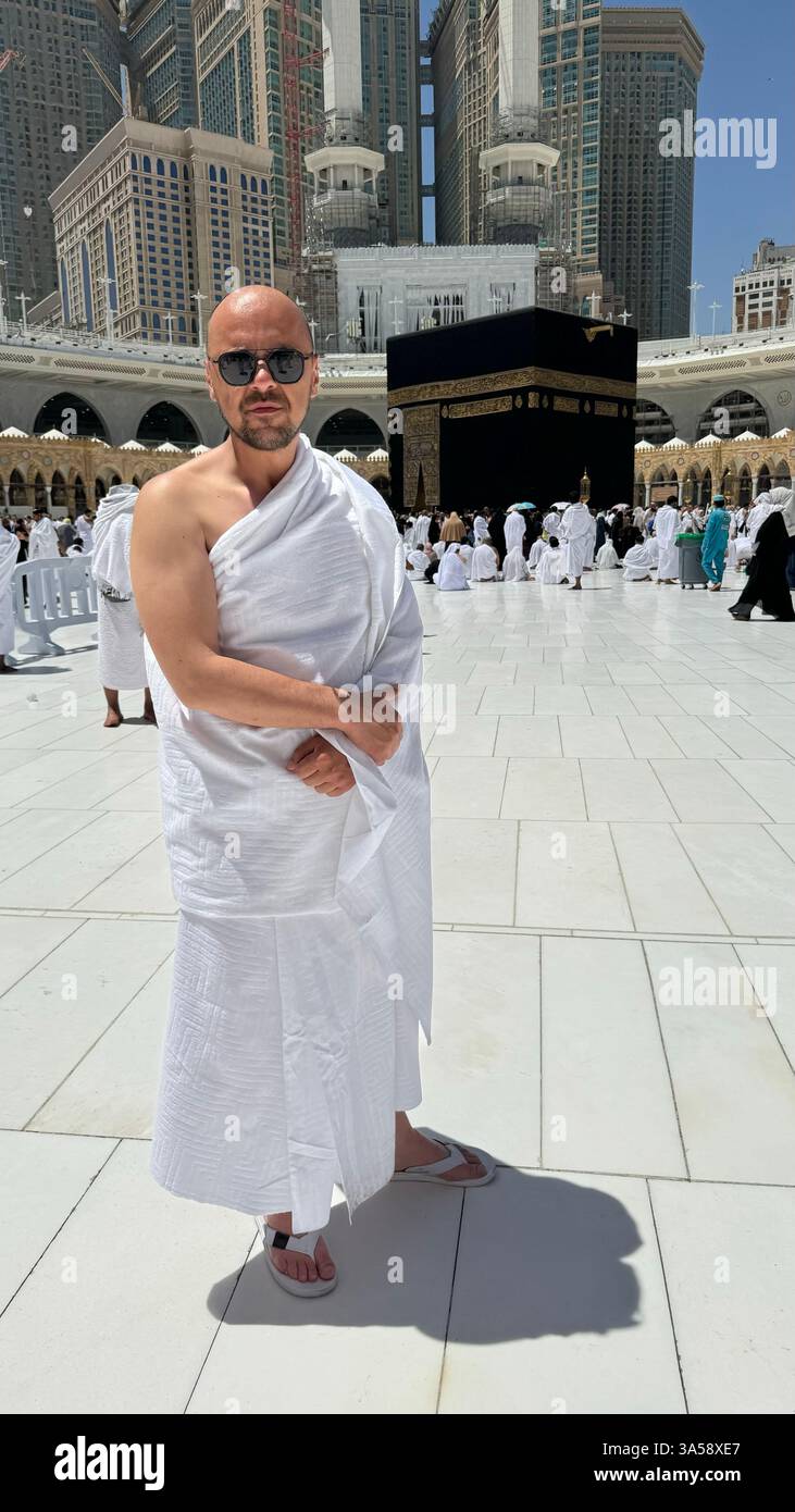 A bald man poses for a photo in front of the Kaaba at noon after ...