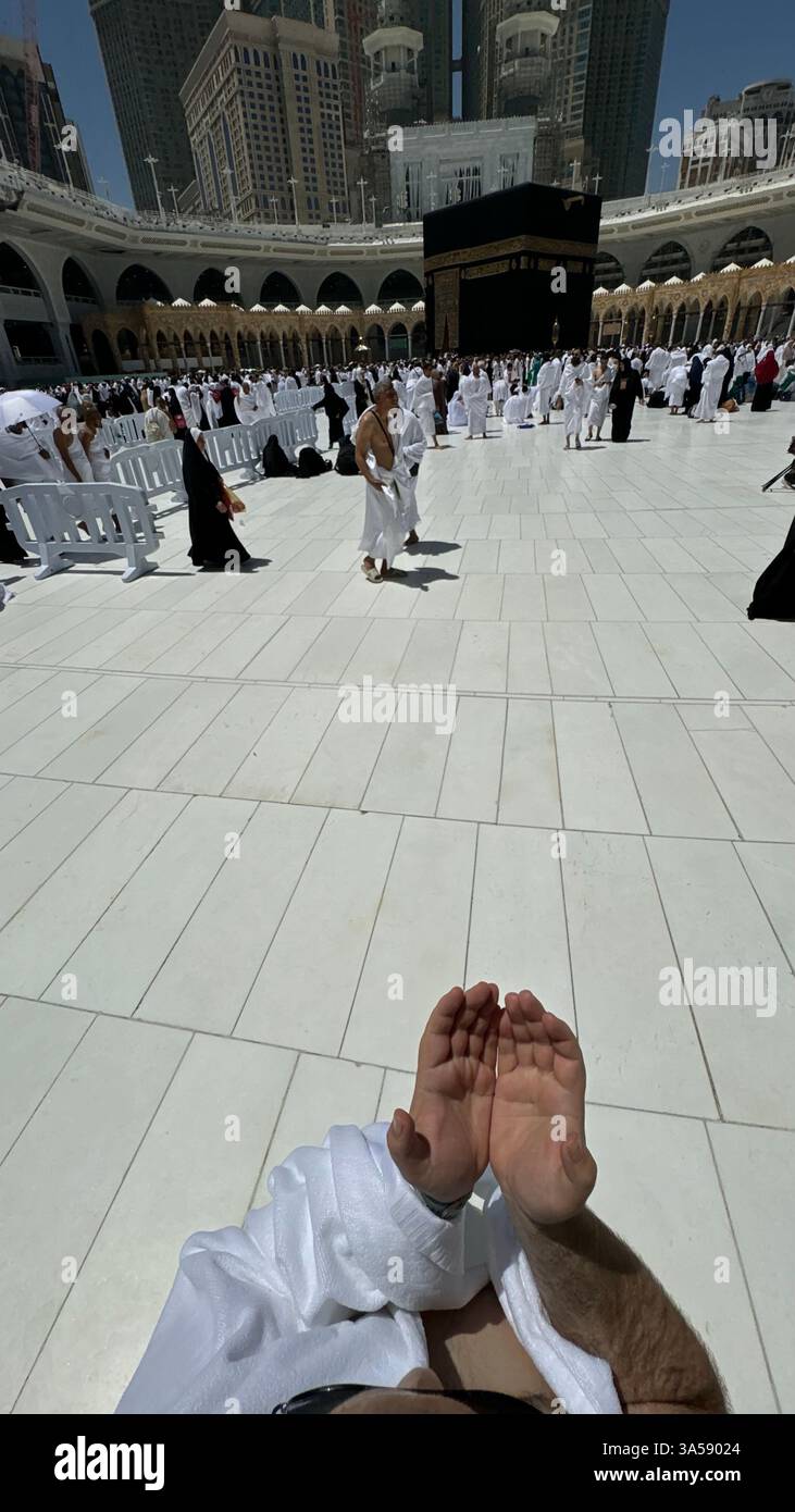A bald man poses for a photo in front of the Kaaba at noon after ...
