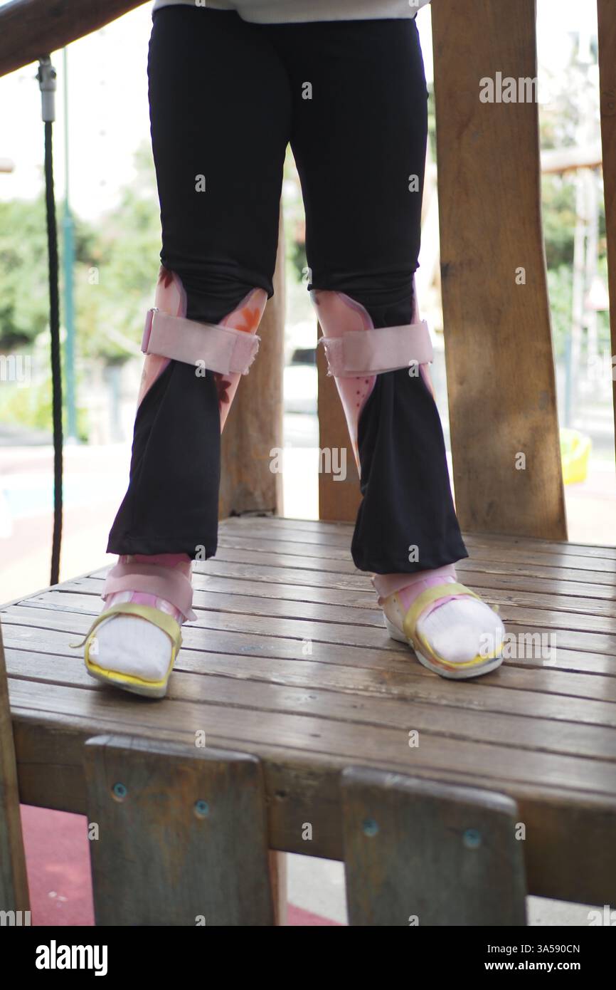 Child using assistive leg supports on playground equipment Stock Photo ...