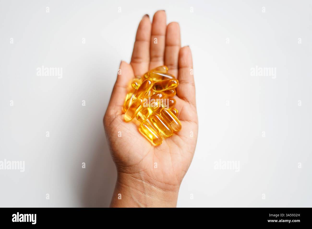 hand holding golden color cod liver capsules Stock Photo - Alamy