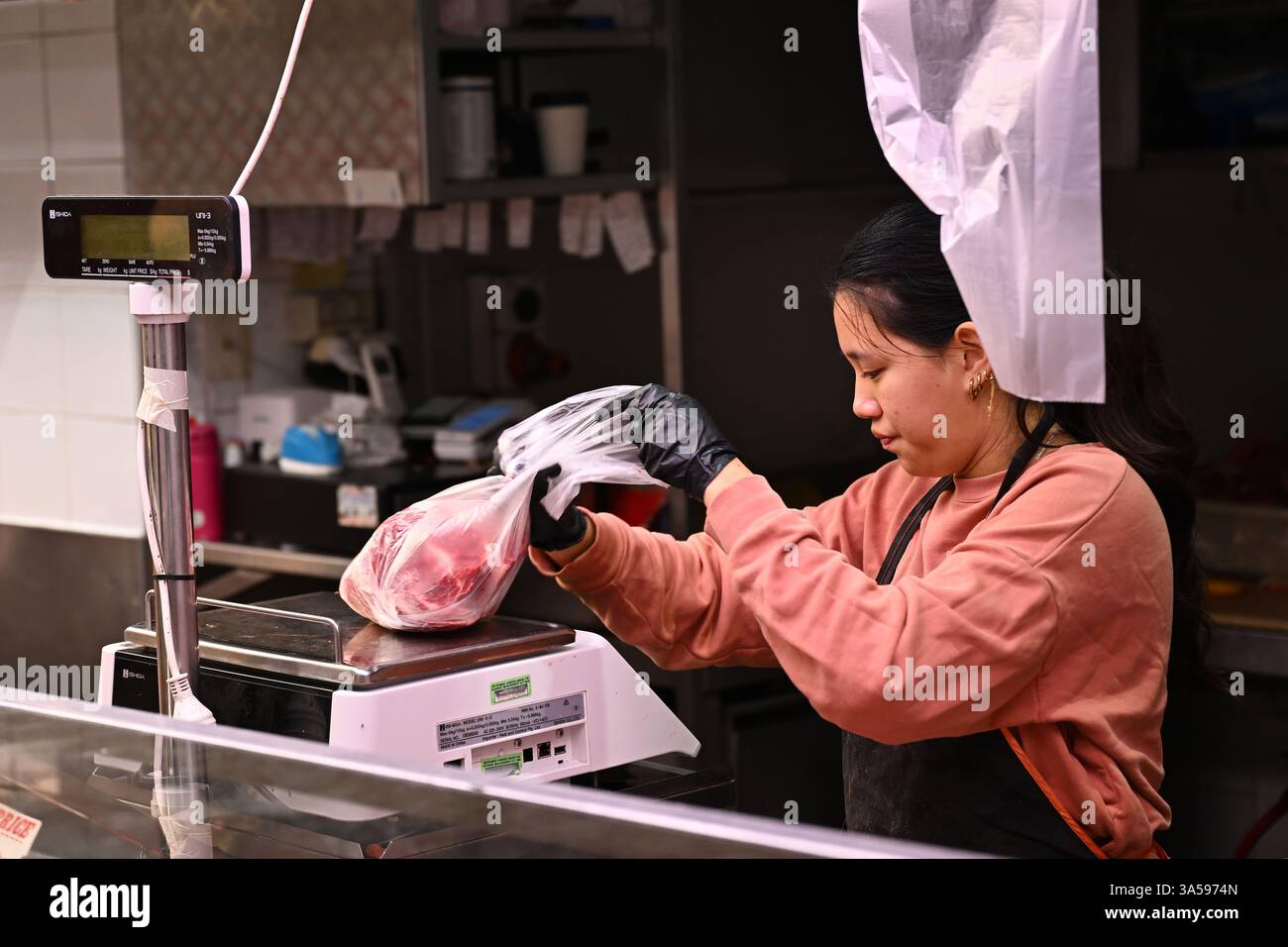 An employee is seen at work at a butchers store at the Queen Victoria ...