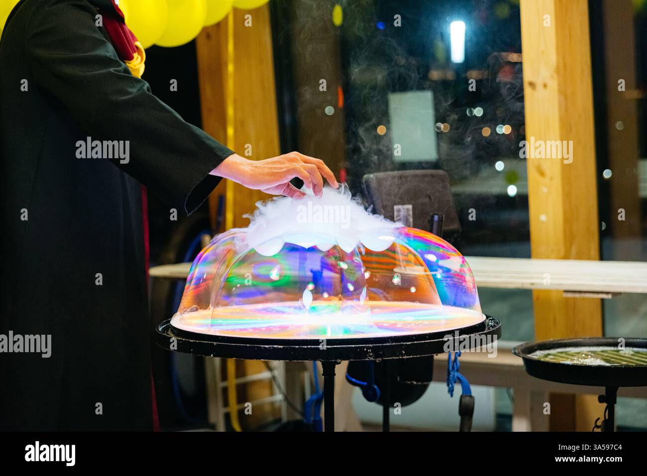 A performer creates smoke-filled soap bubbles under colorful lights ...