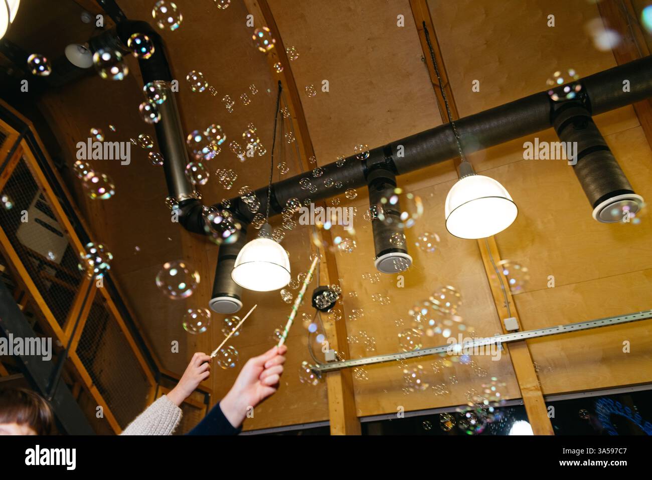 Kids raise bubble wands toward dozens of floating iridescent bubbles ...