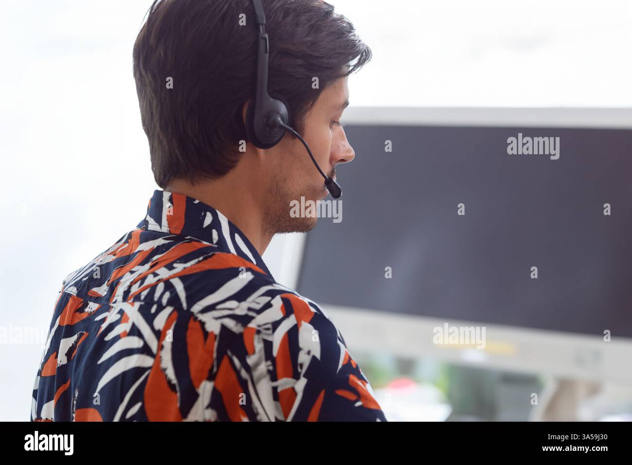 Customer service representative wearing headset assisting clients at ...