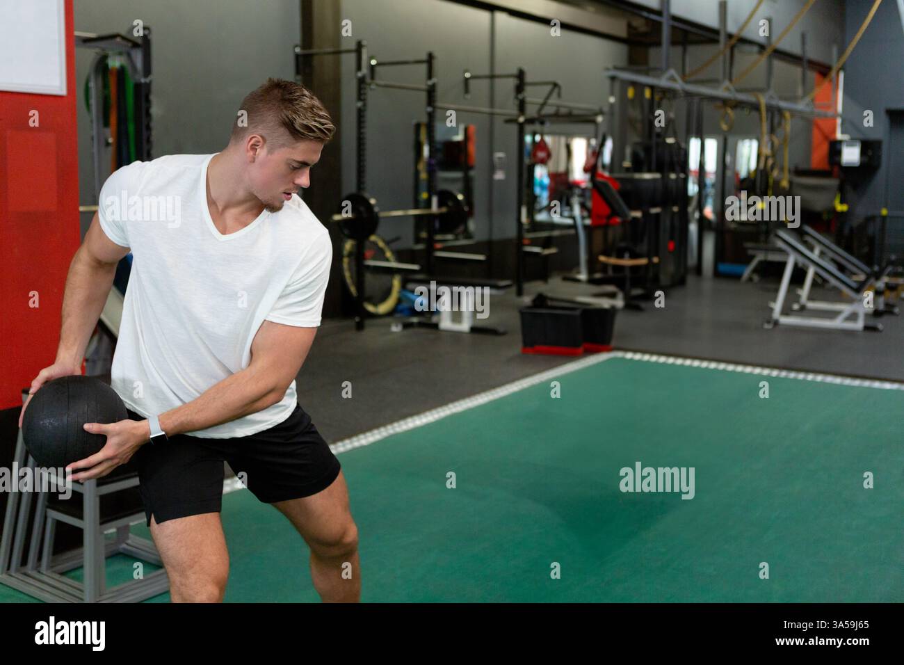 Athletic man exercising with medicine ball in modern gym, focused on ...