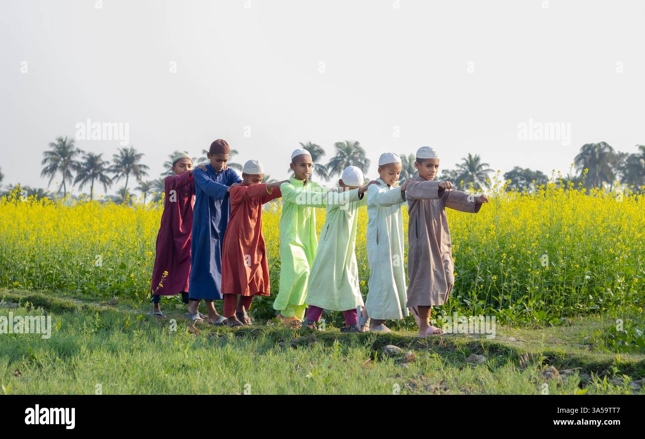 February 15, 2025, Feni, Chittagong, Bangladesh: A group of madrasa students plays in a mustard ...