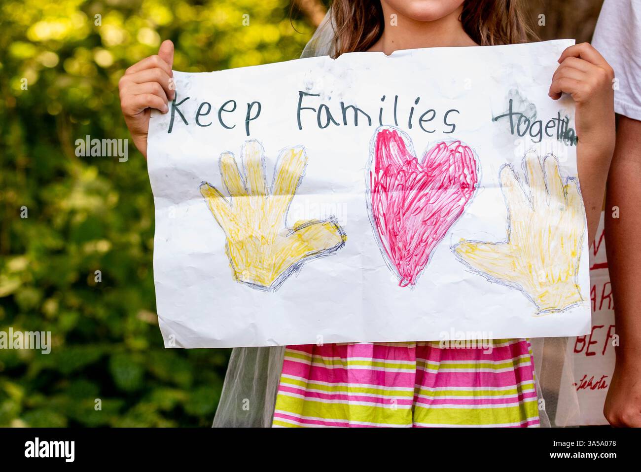A hand written sign with drawings by a child is held up at a political ...