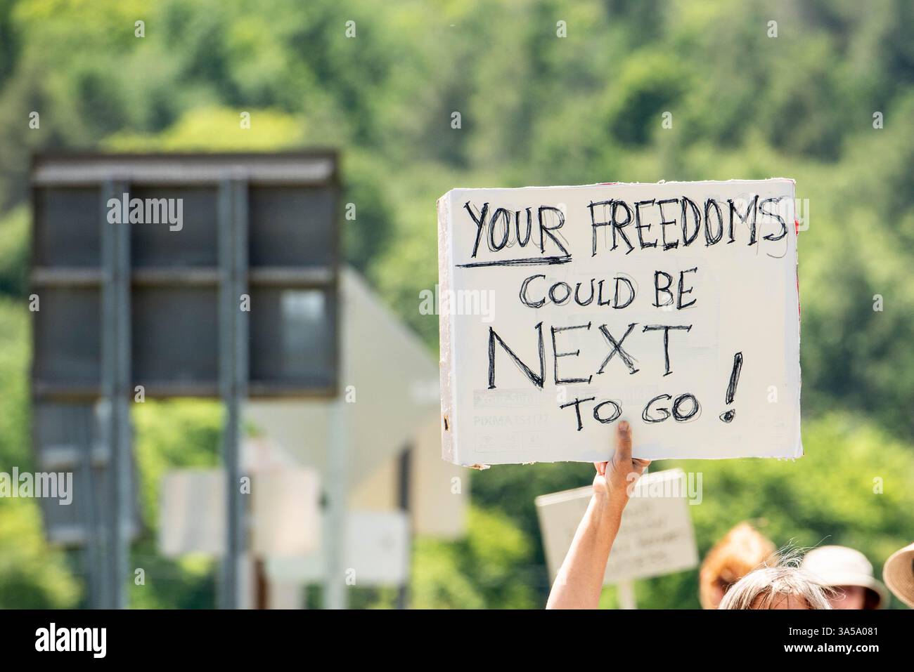 A protestor at a political march holds a sign that warns "Your freedoms ...