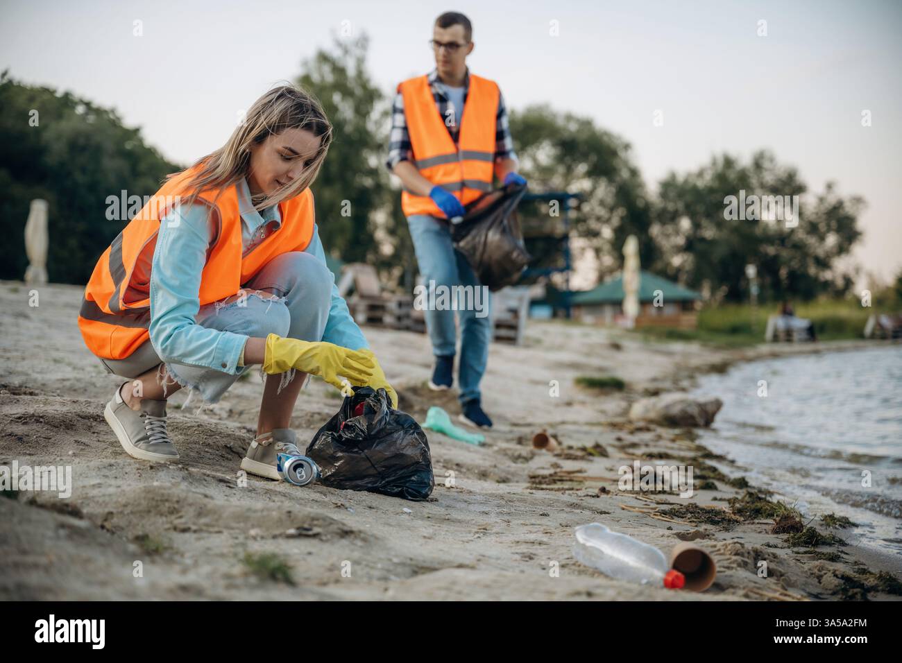 On the shore. A volunteers collects garbage on a muddy beach Stock ...