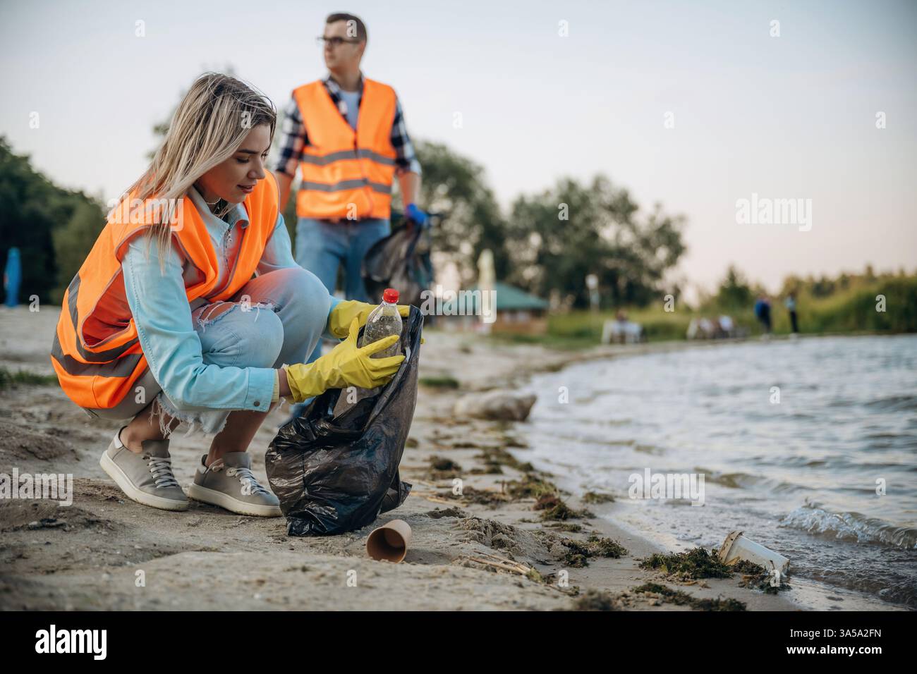 On the shore. A volunteers collects garbage on a muddy beach Stock ...
