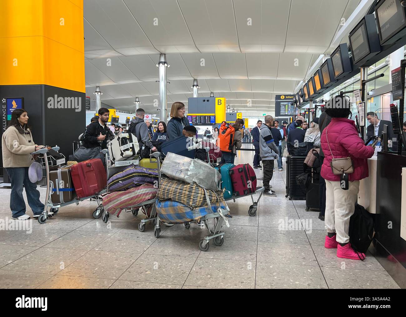 Passengers queue at a check-in desk at Heathrow Terminal 2 in London ...