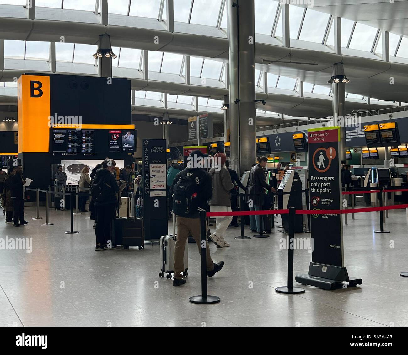 Passengers queue at a check-in desk at Heathrow Terminal 2 in London ...