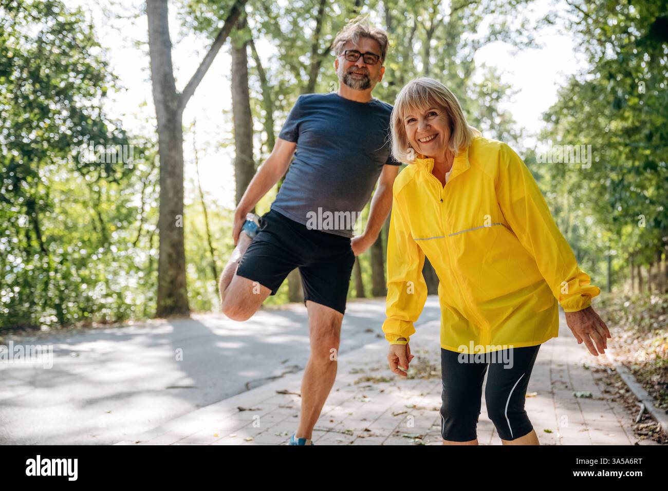 Doing warm up exercises. Senior couple together outdoors at nature ...