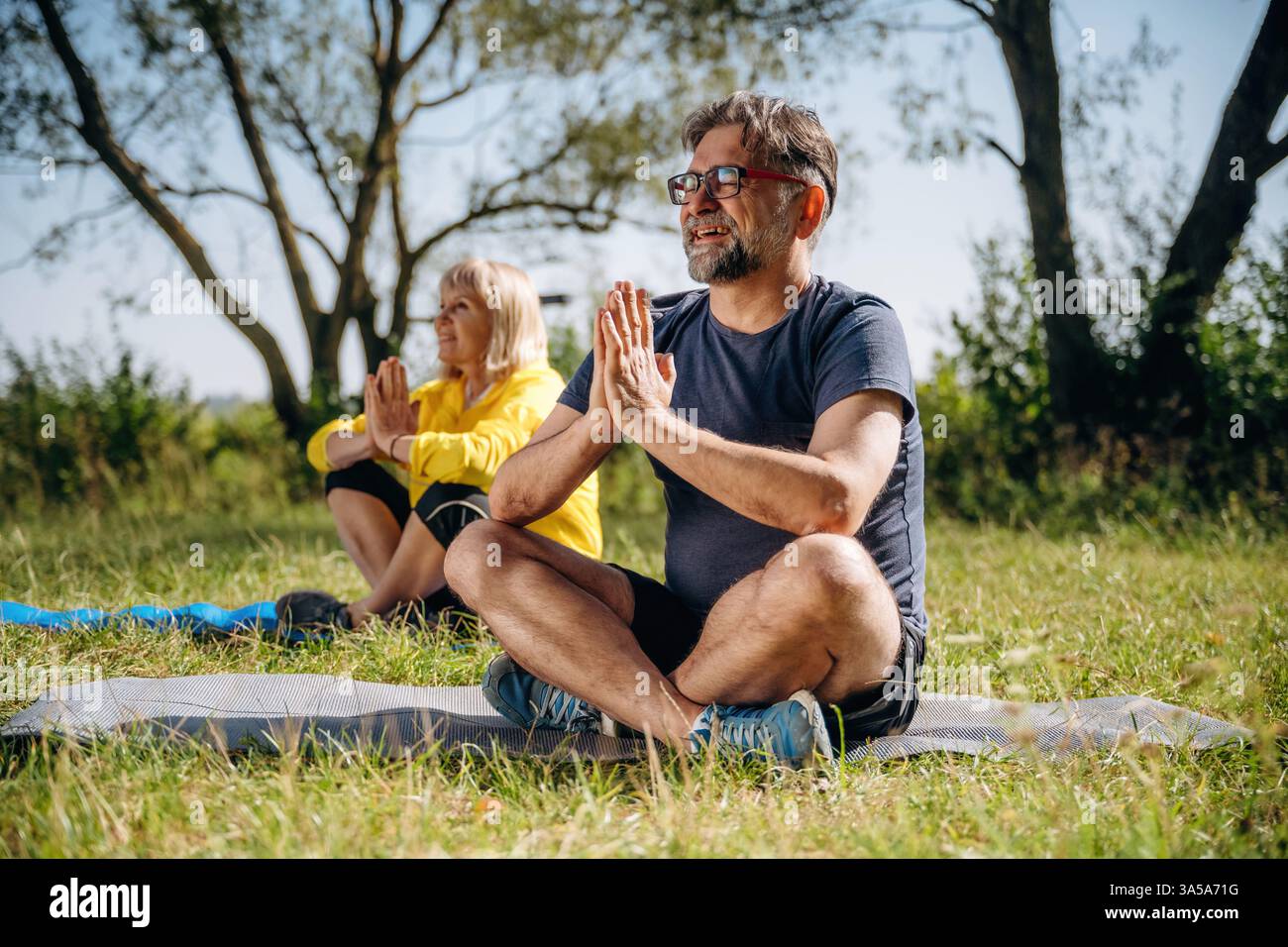 Sitting in the lotus pose, meditation. Senior couple together outdoors ...