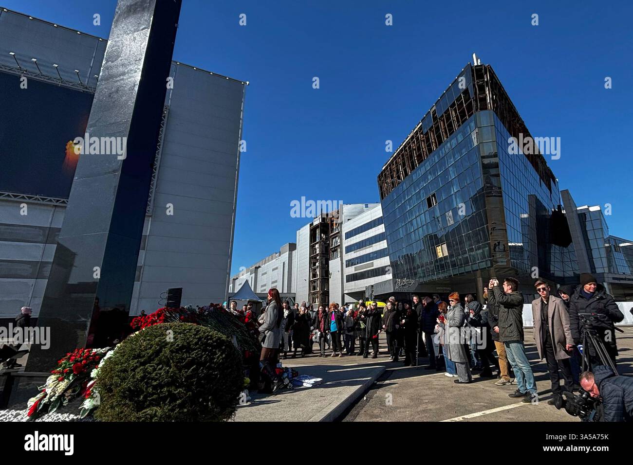 People gather to lay flowers at the newly opened memorial at the Crocus ...