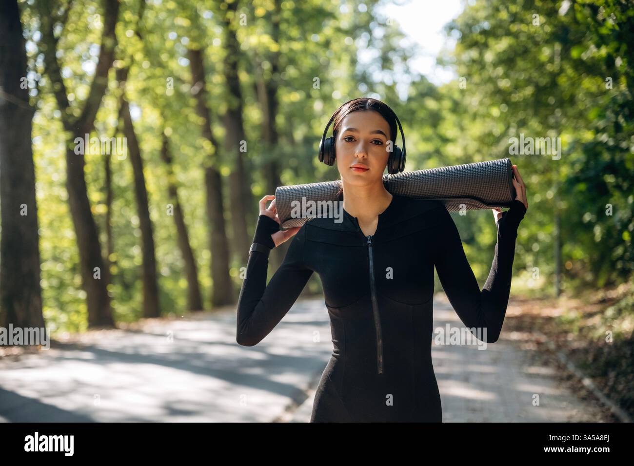 Skinny body type. Standing with yoga mat. Young sportive woman is in ...