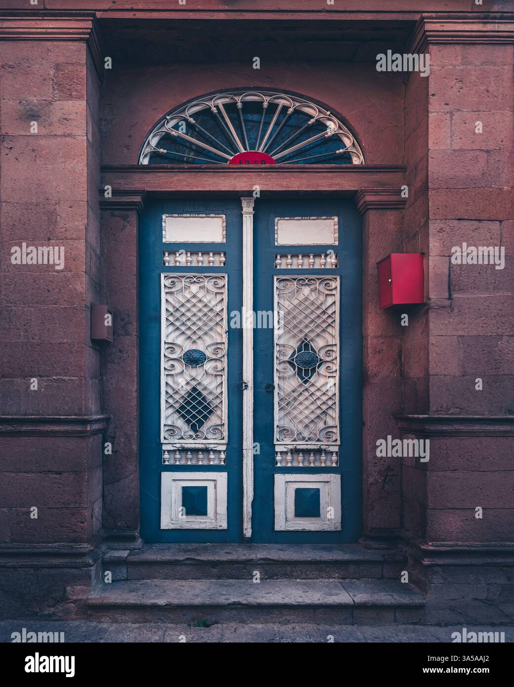 Ornate blue double door with white ironwork and fan-shaped window, set ...