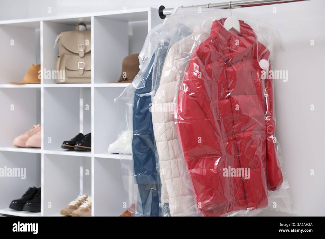 Compressed vacuum bags with clothes hanging on rack indoors Stock Photo ...