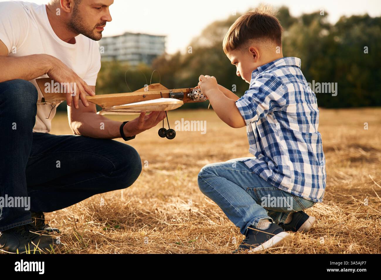 Focused by fixing the toy. Father and son are with wooden plane on the ...