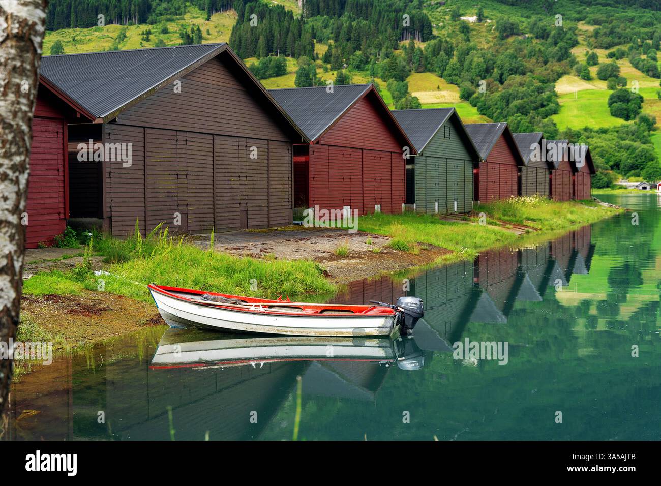 Olden, Norway - July 13, 2023: Colorful boathouses and a small boat on ...