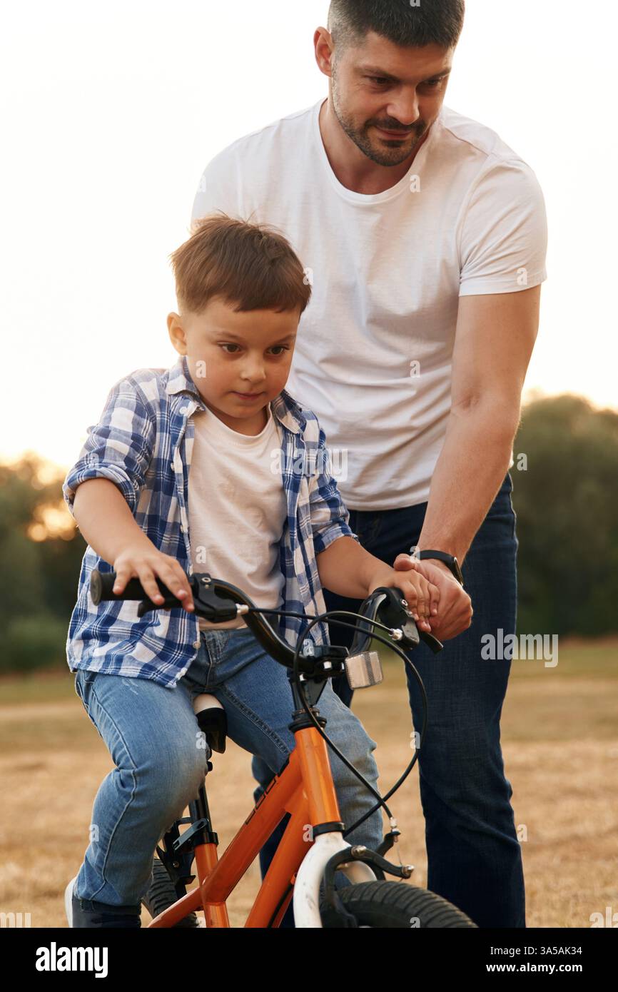 Teaching how to ride. Dad with son are with bicycle on the field ...
