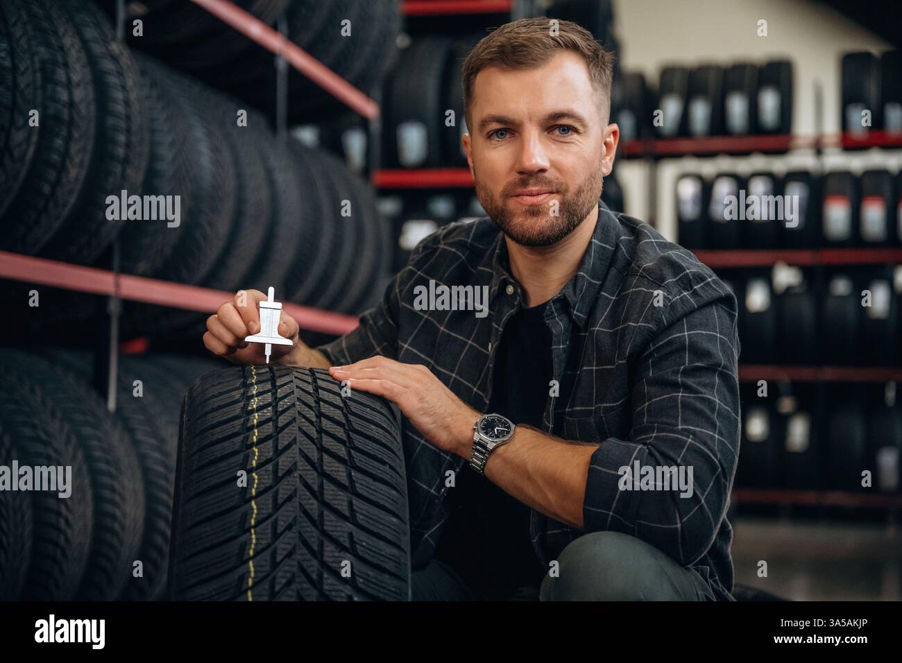 Man worker is maintenance station with tires, wheels Stock Photo - Alamy