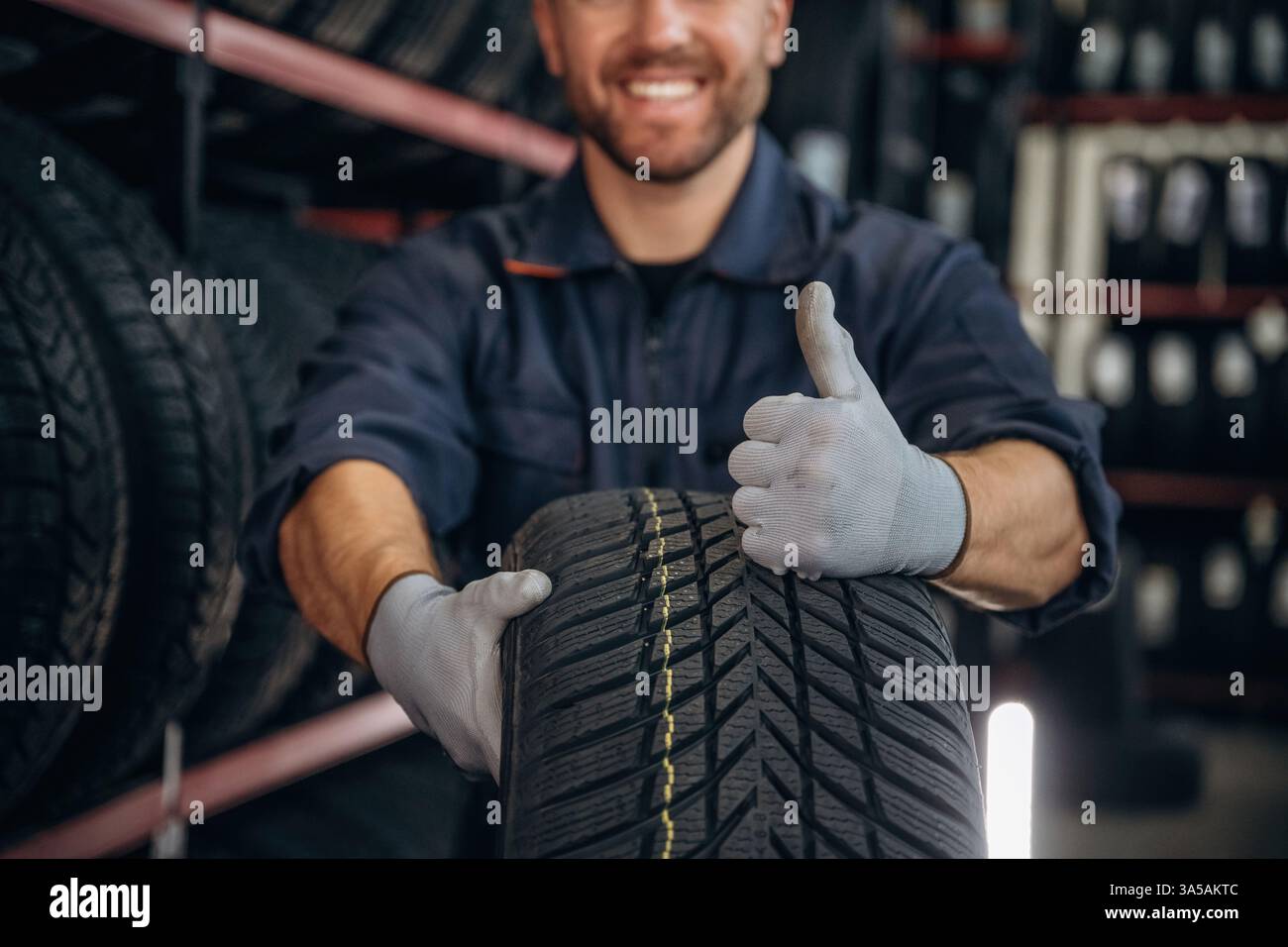 Focused close up view, thumb up, holding a tire. Man worker is ...