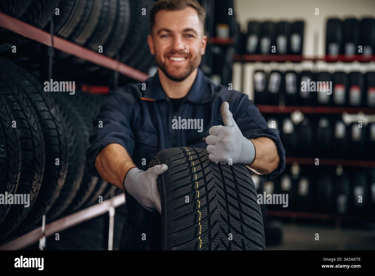 Man worker is maintenance station with tires, wheels Stock Photo - Alamy