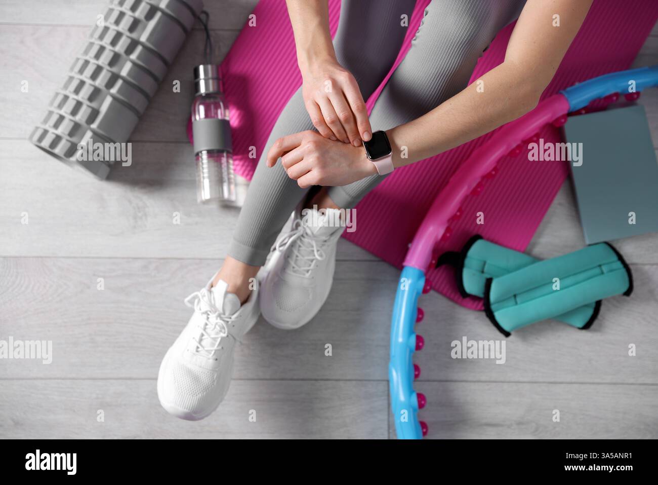 Woman with smart watch and gym equipment on floor indoors, top view ...