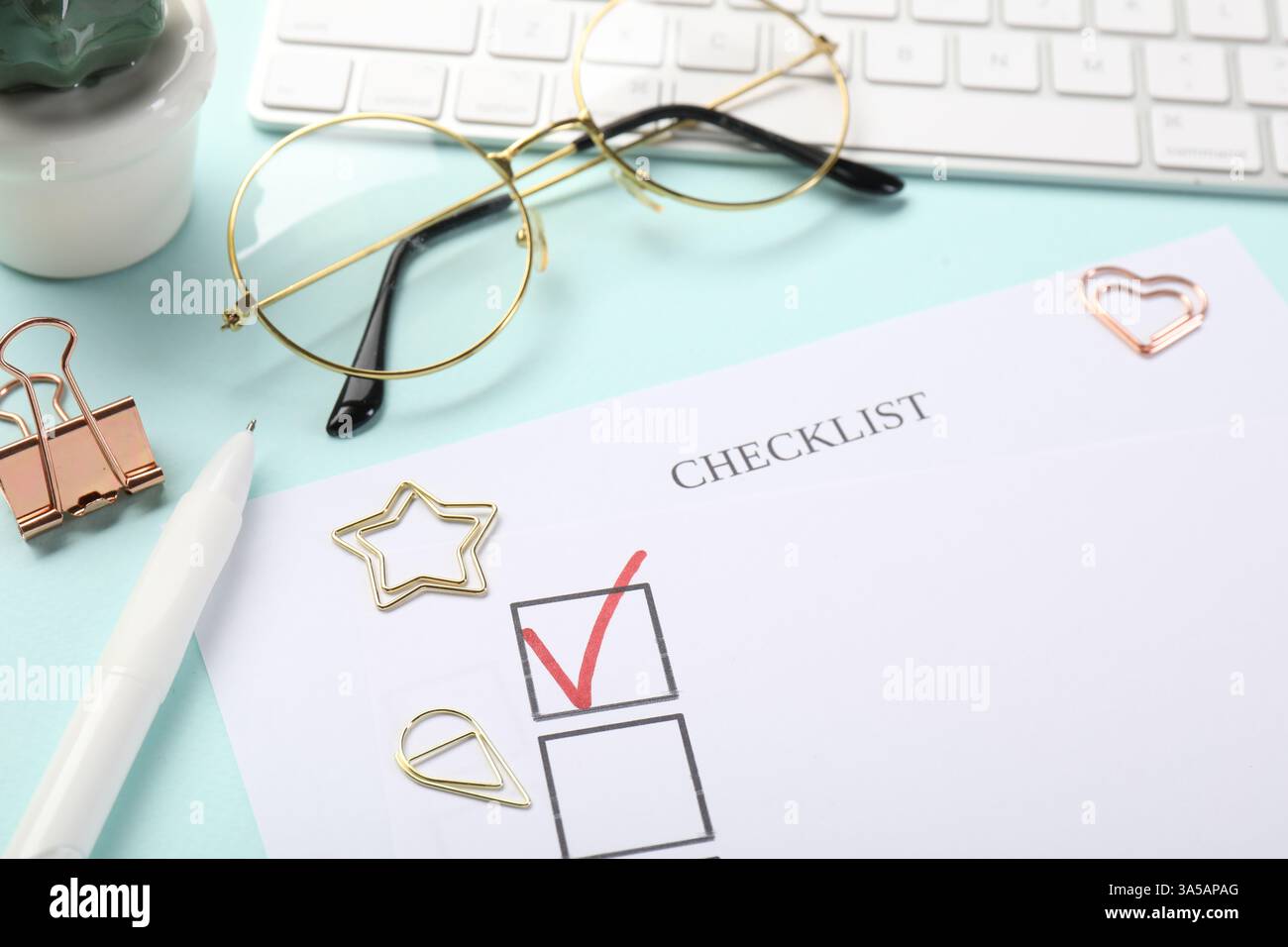 Checklist with marked checkbox, keyboard, glasses and paper clips on ...