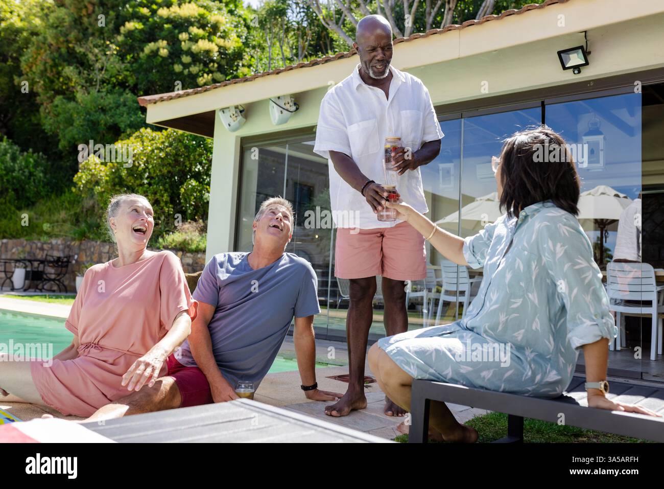 Group of seniors enjoying drinks and laughter by poolside at home Stock ...