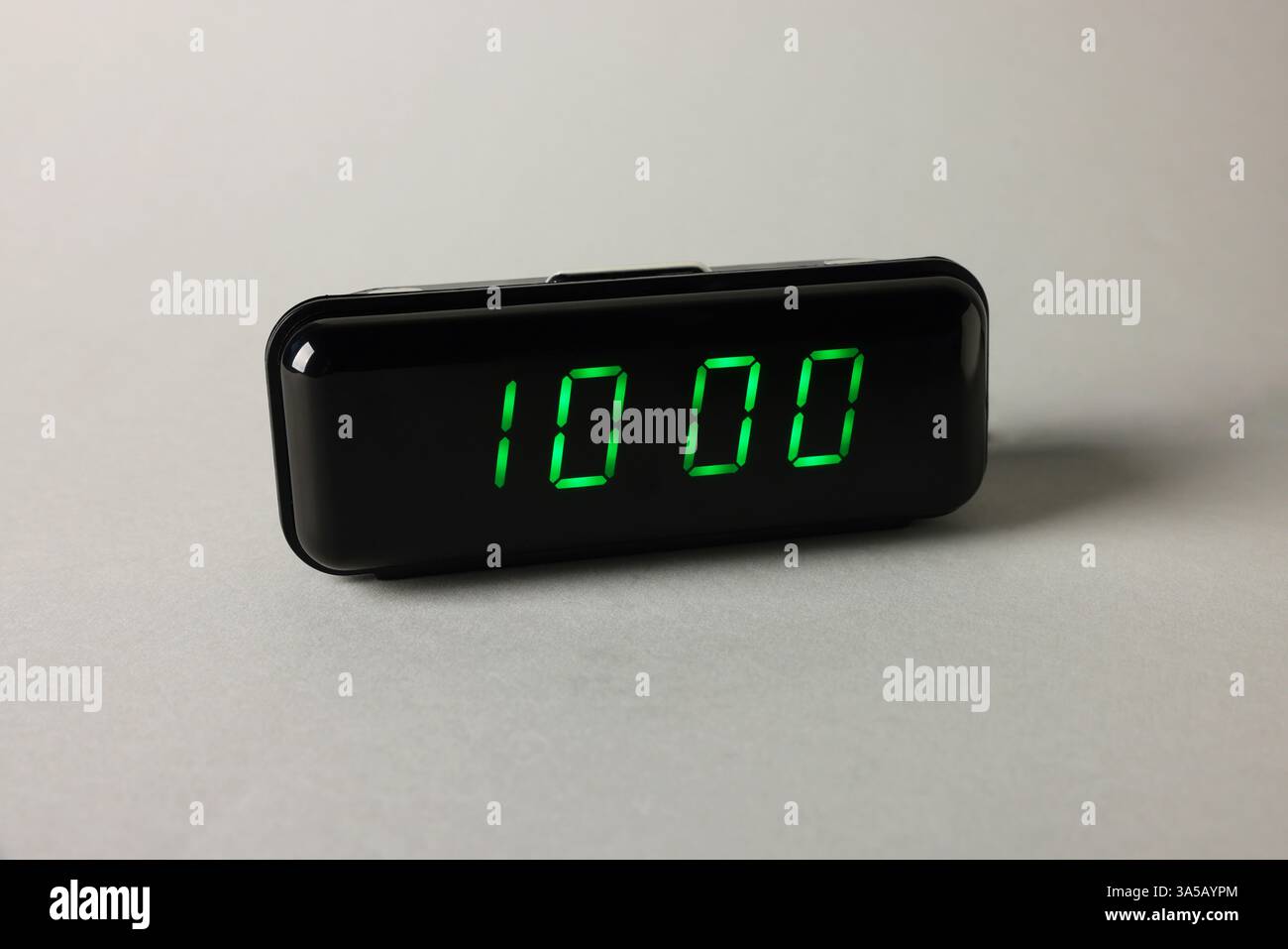 Digital alarm clock showing 10:00 o'clock on grey background Stock ...