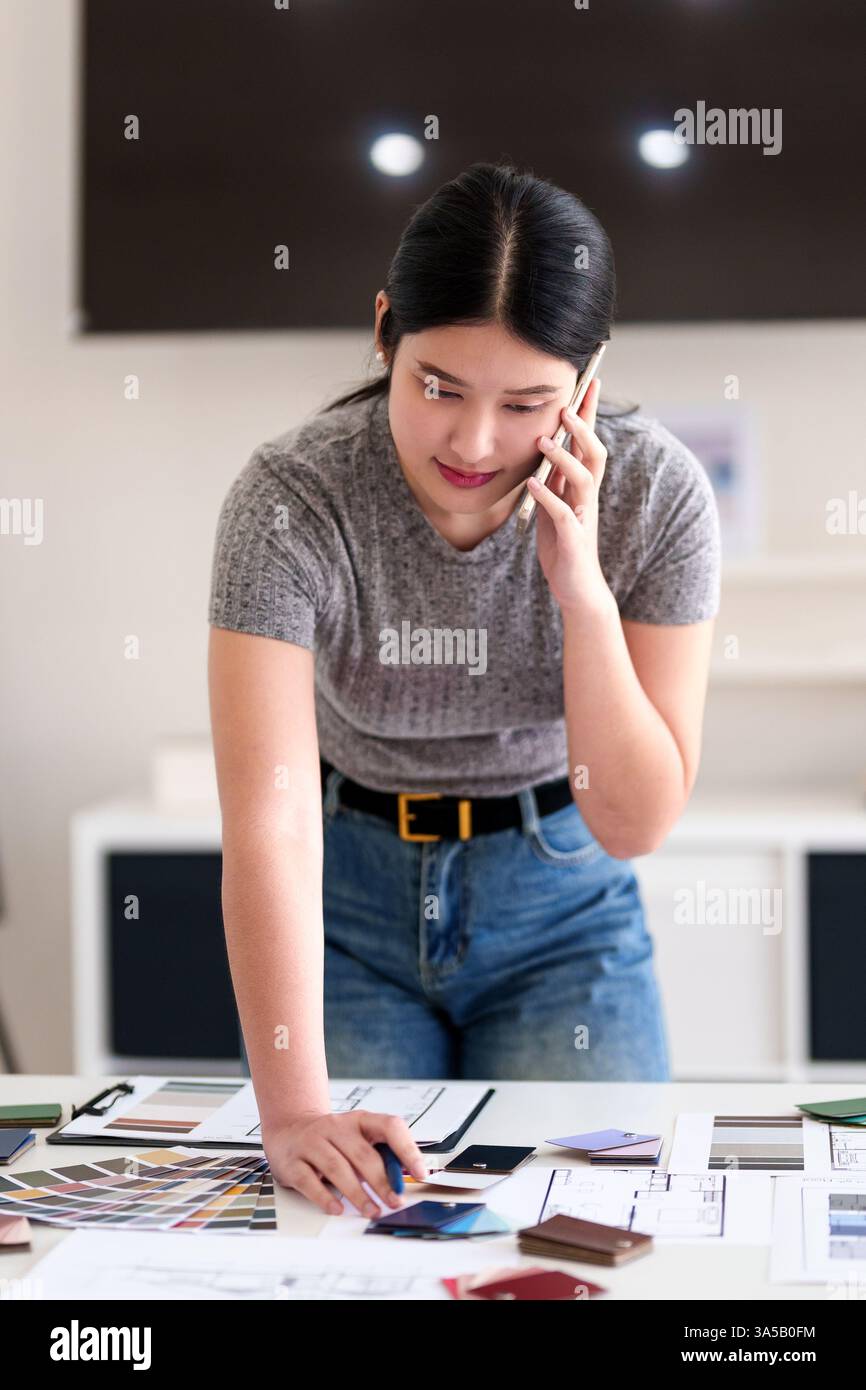 Interior designer discussing project on phone while reviewing material ...