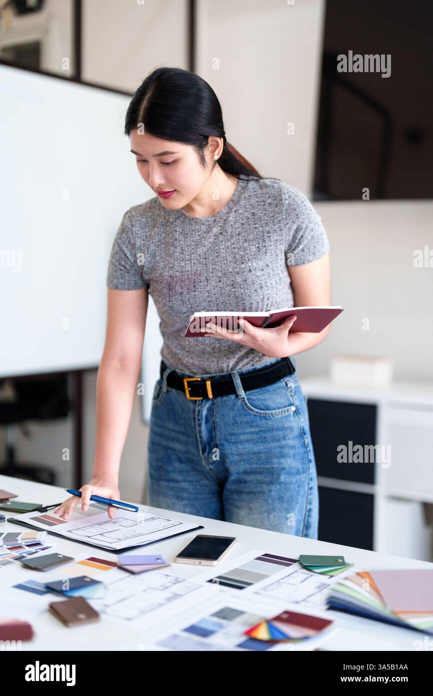 Young architect selecting materials and color swatches while standing at modern interior design ...