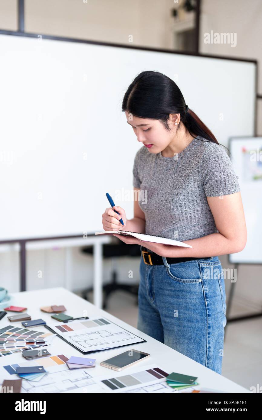 Young architect selecting materials and color swatches while standing at modern interior design ...