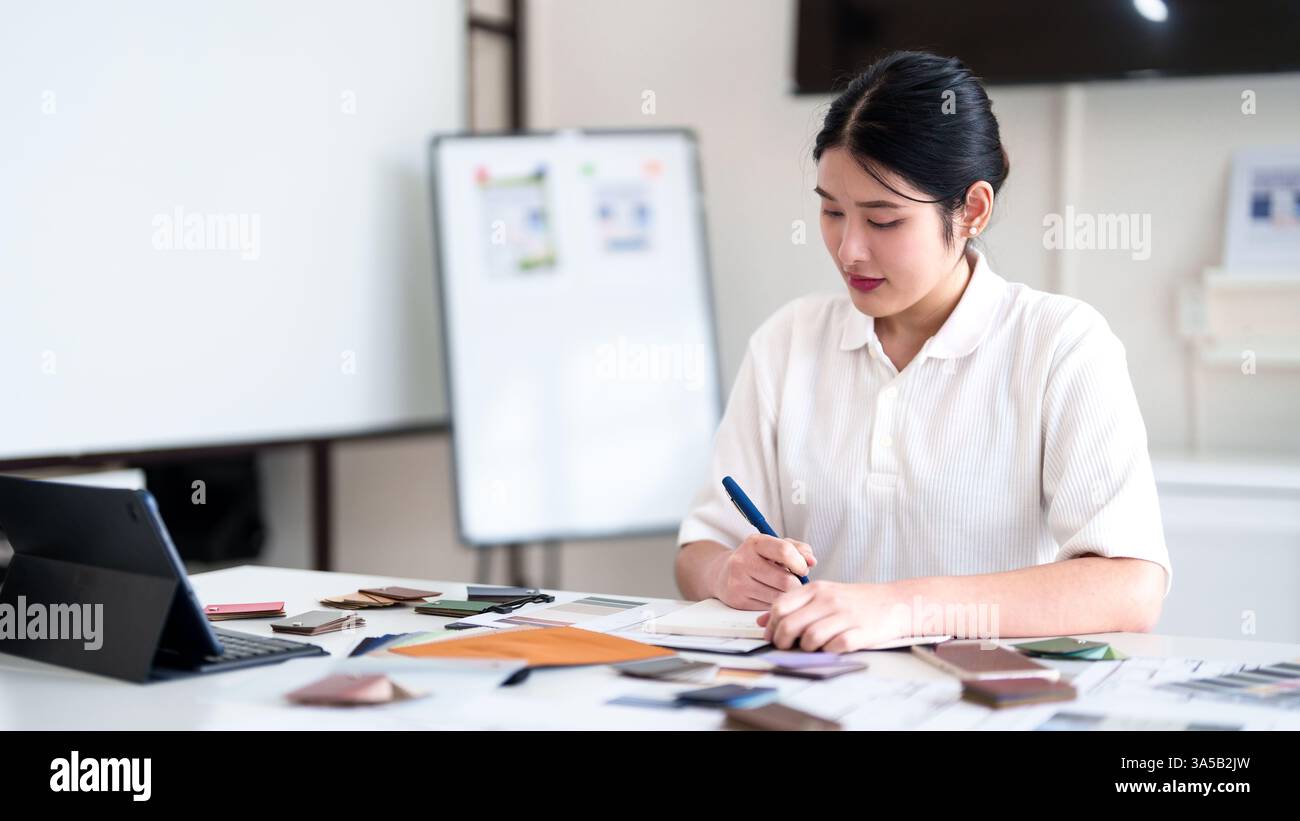 Focused interior designer planning color concepts and working with material samples at design ...