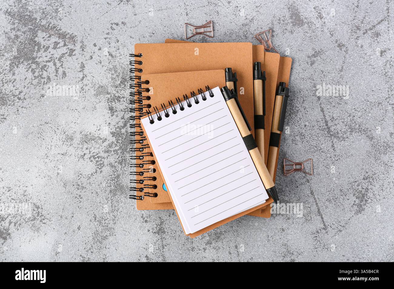 Stack of notebooks, pens and bow paper clips on grey background Stock ...