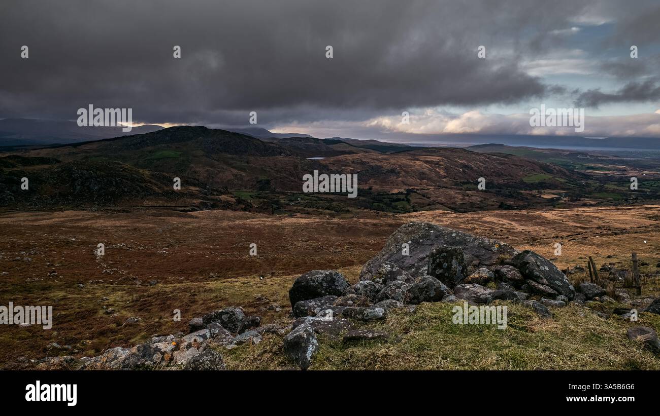 Vast expanses of rolling hills stretch out under a moody sky filled ...