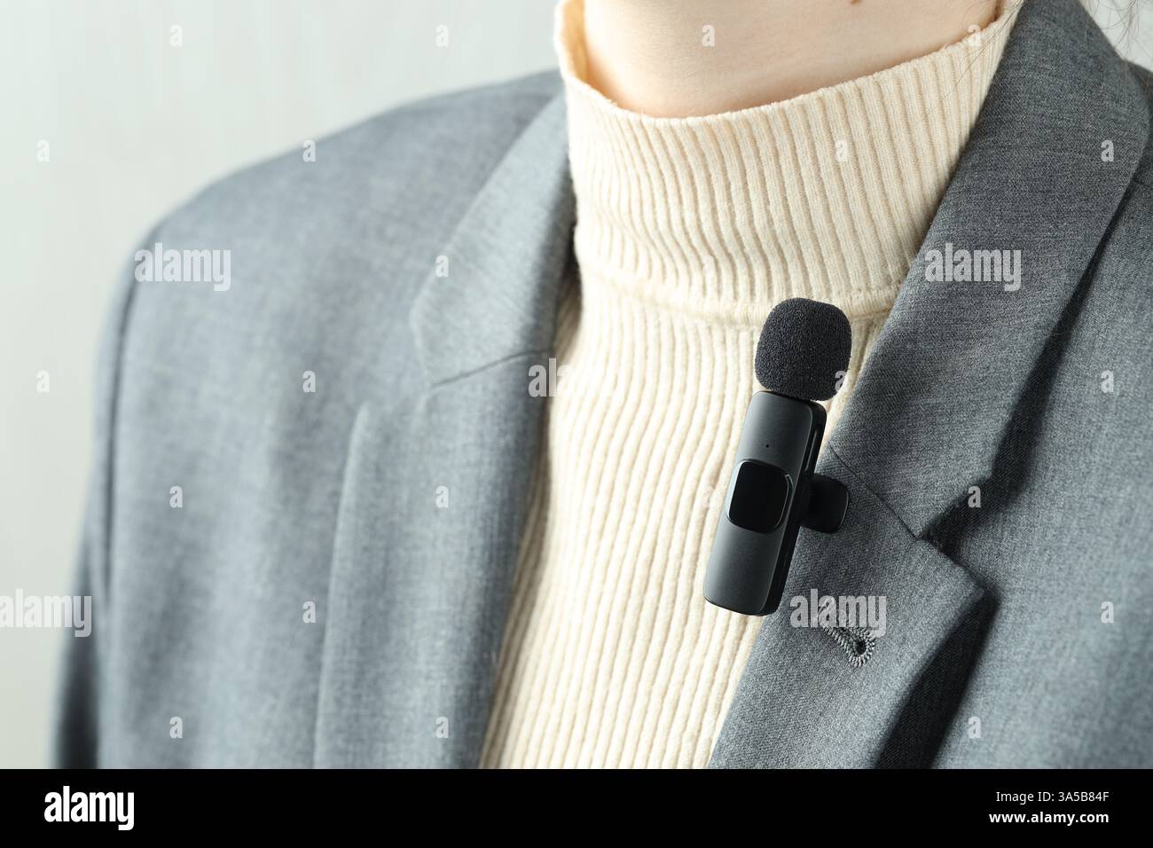 Woman with lavalier microphone on her shirt against light grey ...