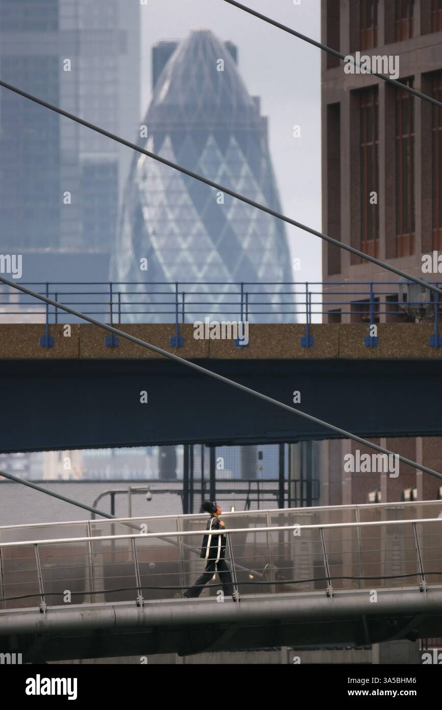 Pedestrians crossing South Dock footbridge with The Gherkin as backdrop ...
