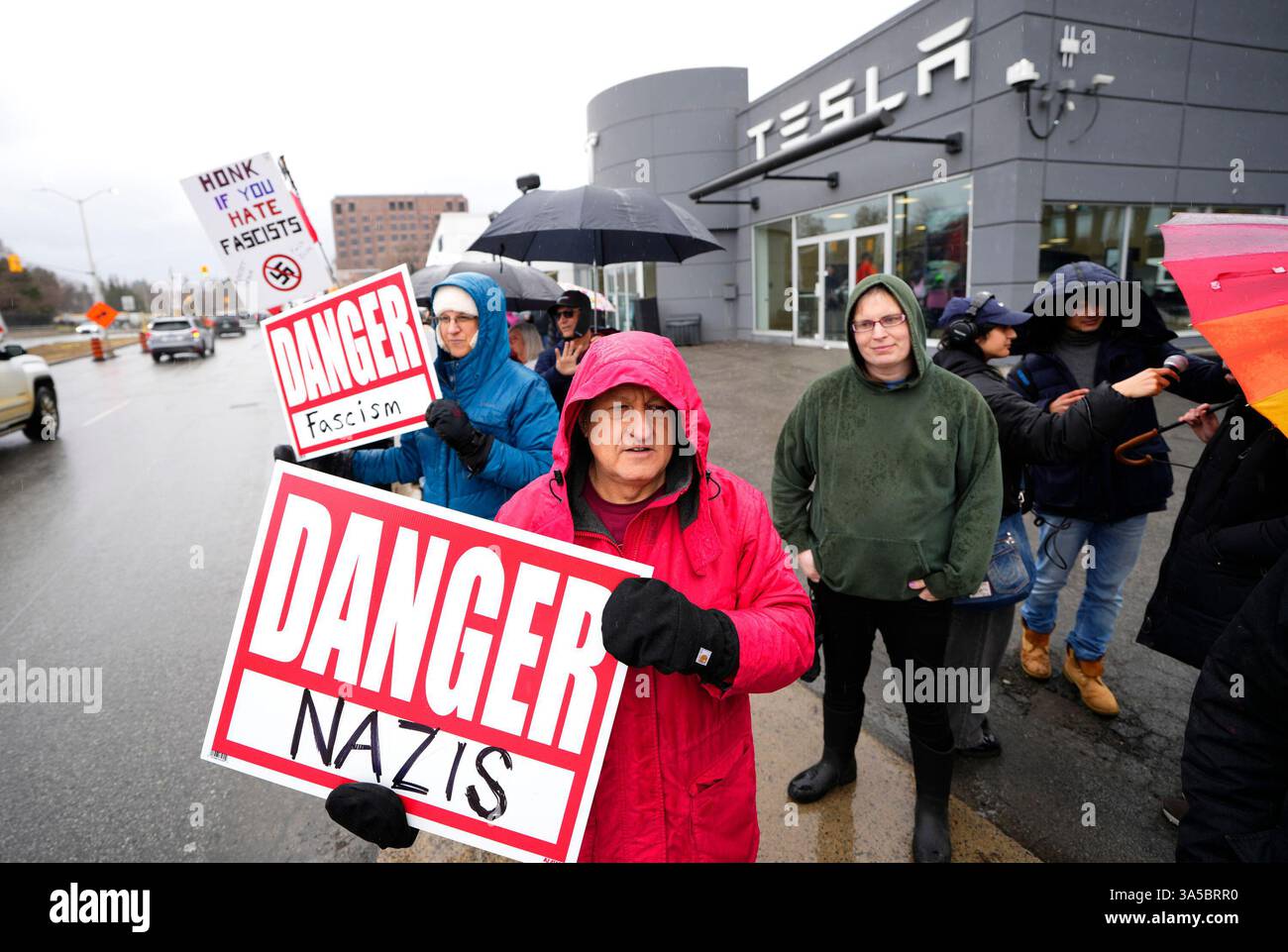 People attend a protest rally outside a Tesla dealership in Ottawa ...
