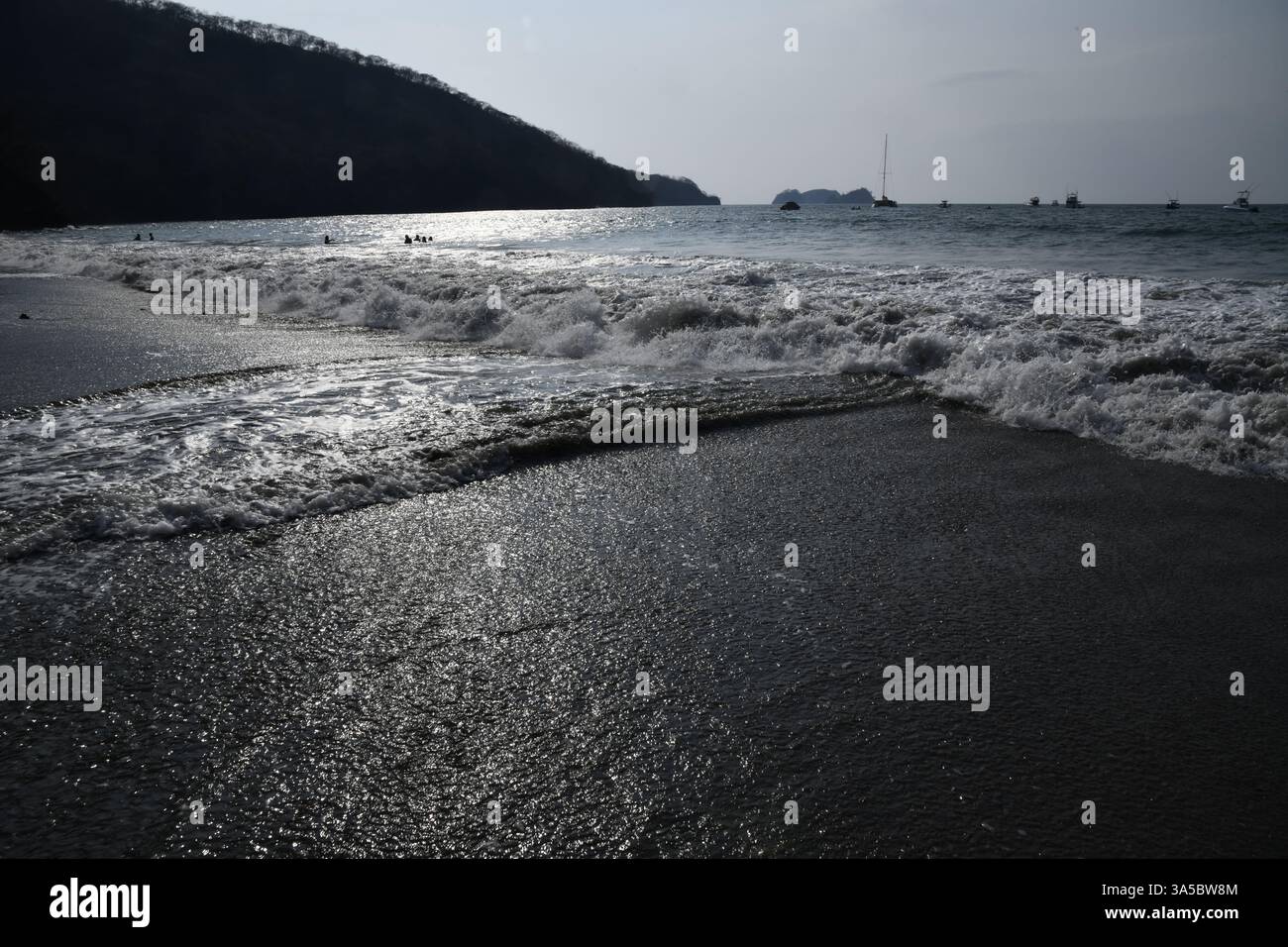 Surf breaking on beach in Costa Rica with evening sun shining on ...