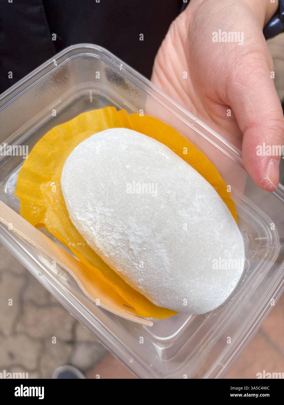 Close-up of a mango mochi dessert in a clear plastic container, with a ...