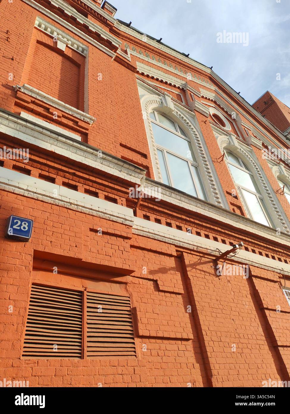 An ornate red brick structure with arched windows, white decorative ...