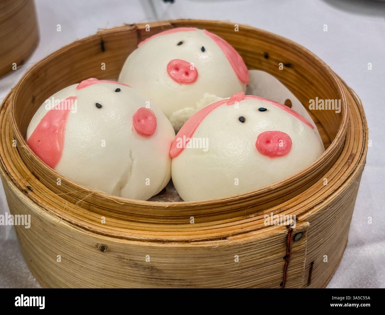 Three steamed buns shaped like pigs in a bamboo steamer, a Hong Kong ...