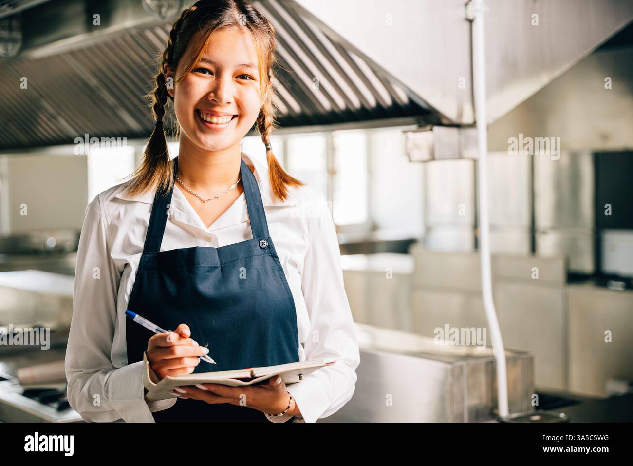 Professional chef's portrait in commercial kitchen. Holding note book ...