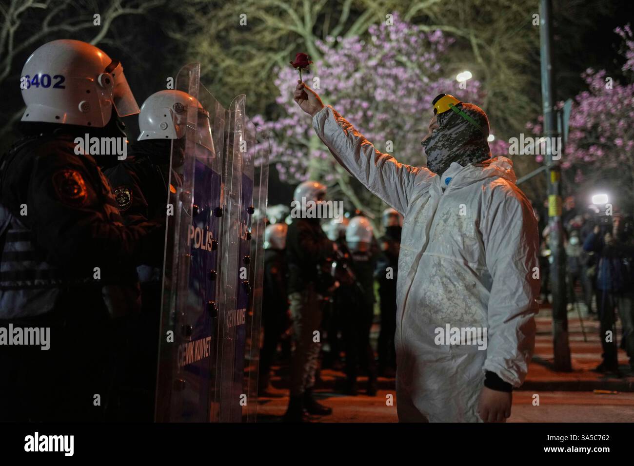 A protesters holds up a flower as stands in front of riot police ...