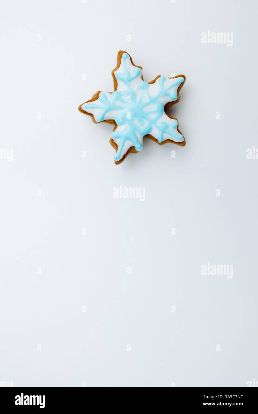 A beautifully crafted snowflake-shaped cookie rests against a pristine ...