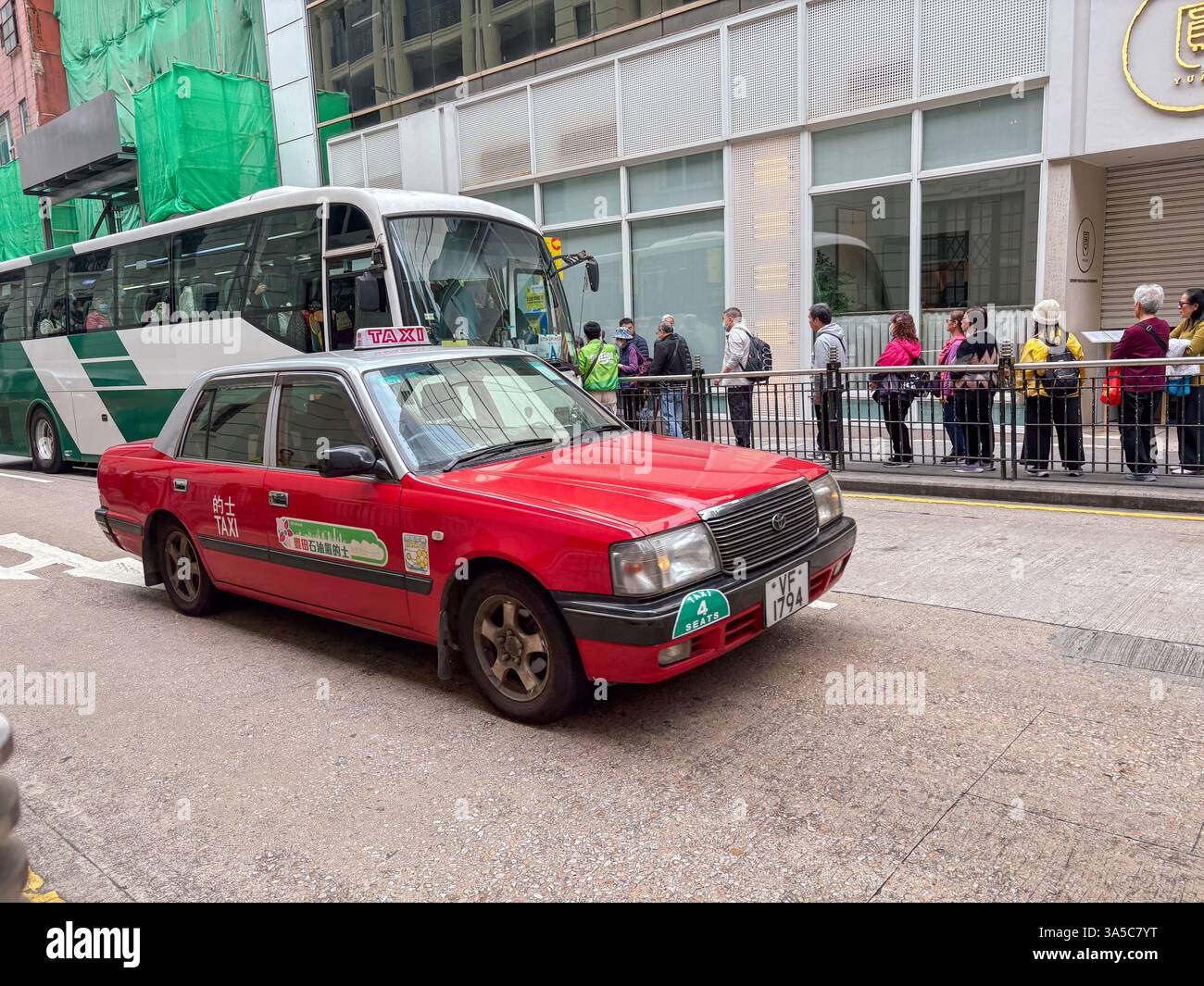 Tour bus, red taxi and people waiting in line on a street in Hong Kong ...
